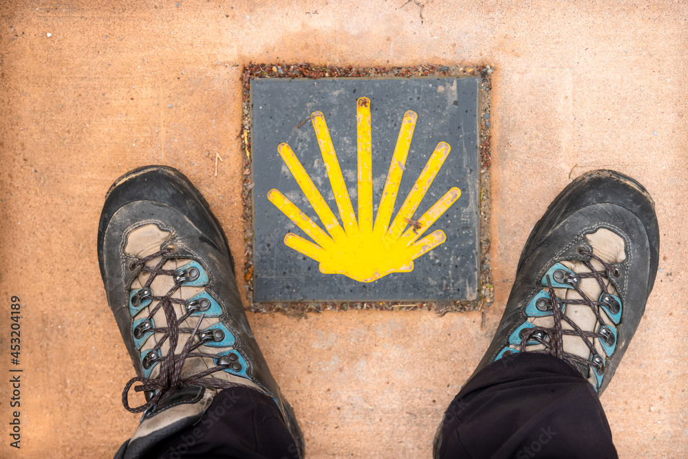 Hiking Boots Feet on Trail with Scallop Shell Way Mark on tthe Way of ...
