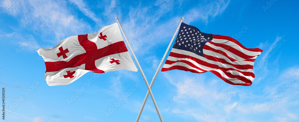 flags of USA and Georgia waving in the wind on flagpoles against the ...