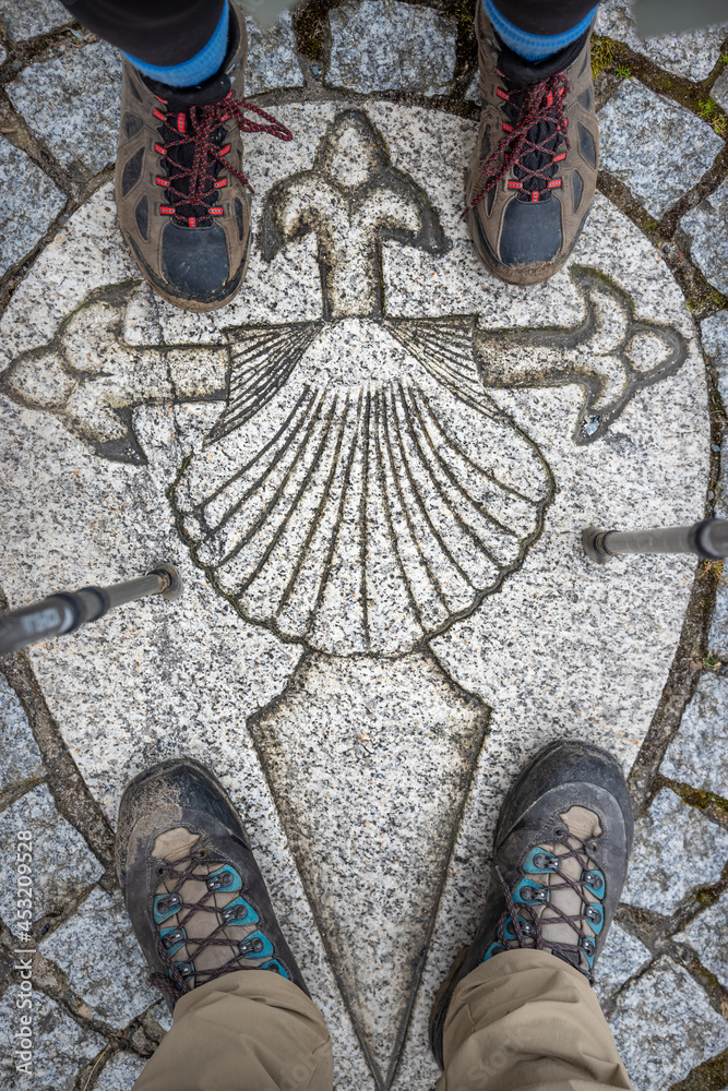 Feet of Two Pilgrims in Hiking Boots standing beside the Symbol Cross ...