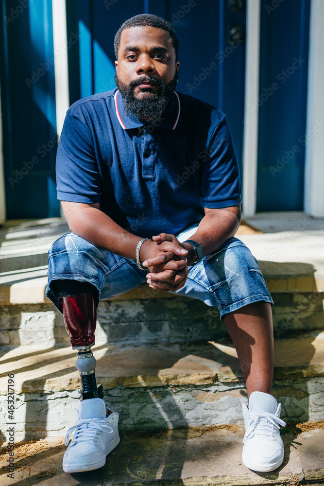 Black man with prosthetic leg sitting at front porch of new home ...