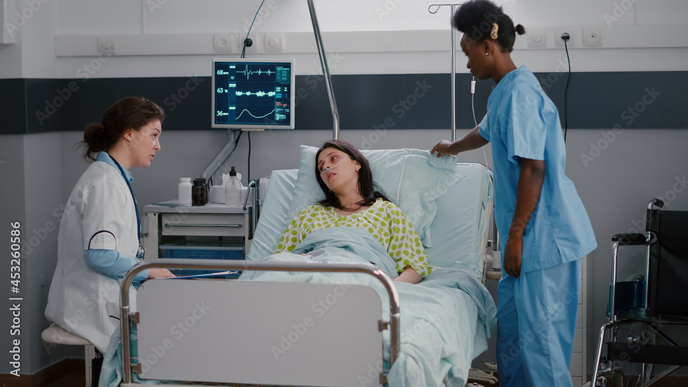 Nurse with dark skin helping patient to sit comfortable in hospital ...