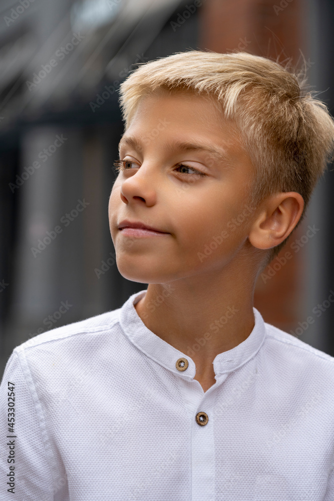 Small fashionable boy poses in front of red brick building on street ...