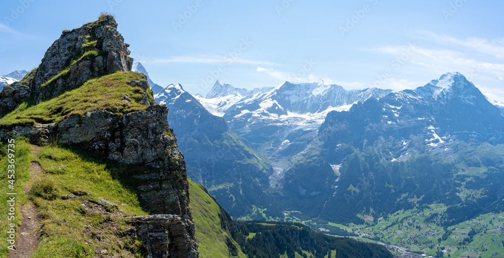 un promontoire vert et rocheux devant une chaine montagneuse aux ...