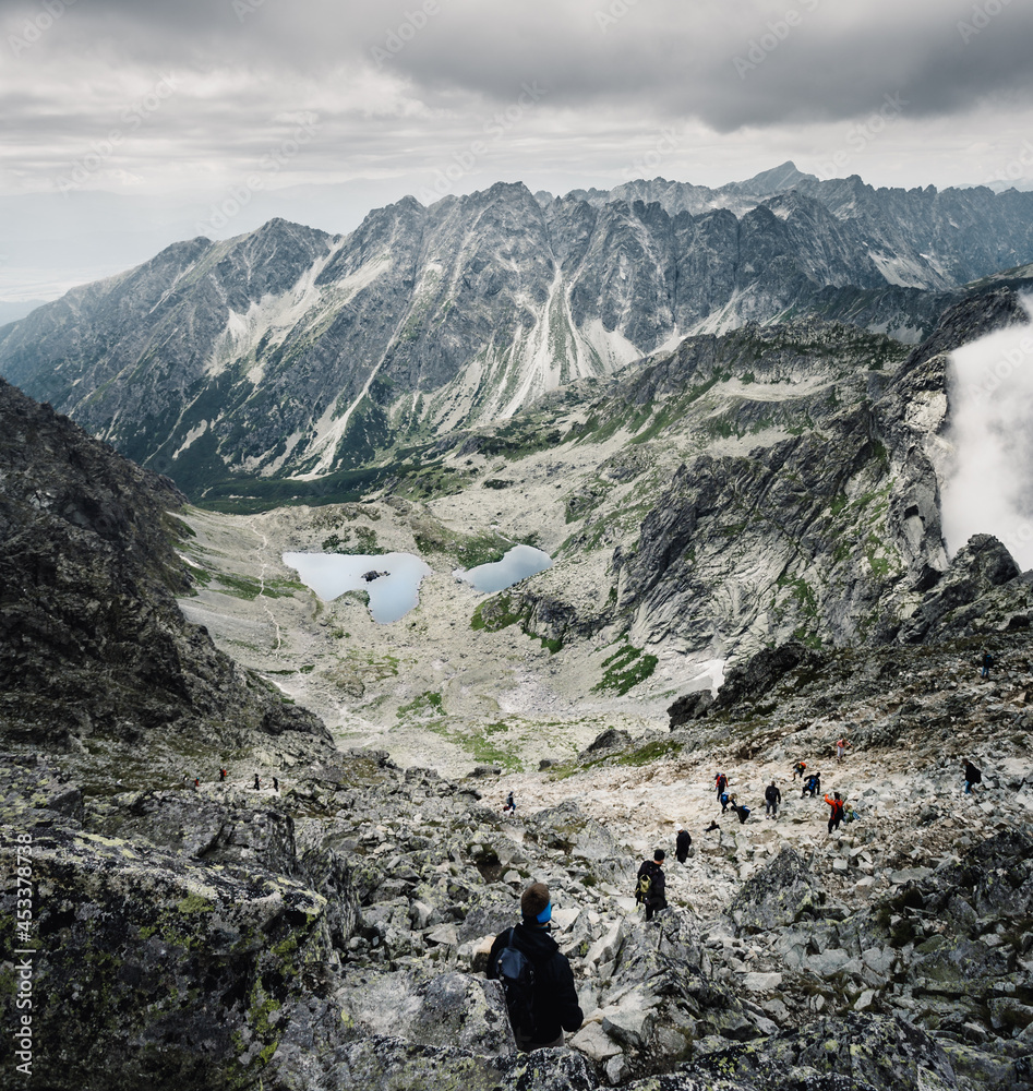 Group of hikers in row descending from top of mountain into valley ...