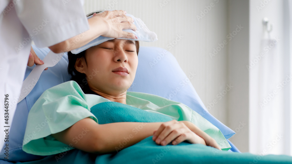 An asian young beautiful female patient getting sick, lying and ...