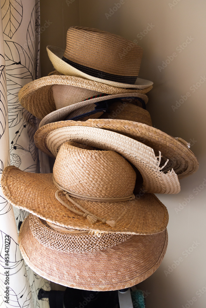 Vertical view of pile of different models of straw hats in the corner ...