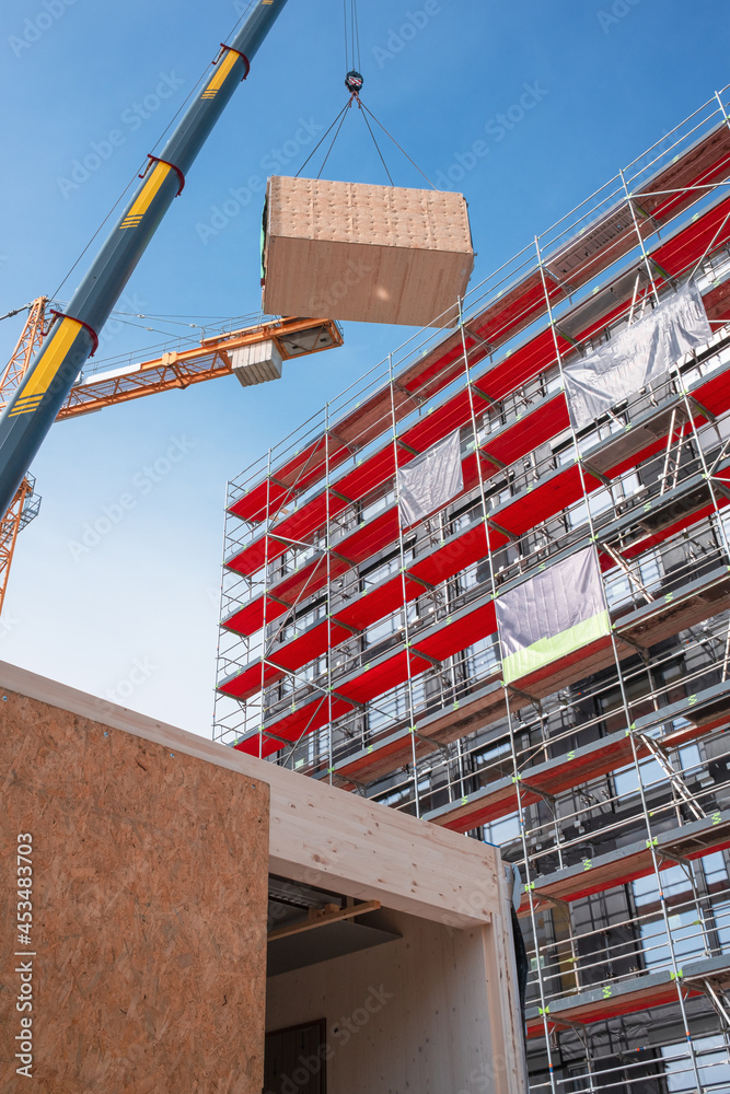 Crane lifting a wooden building module to its position in the structure ...