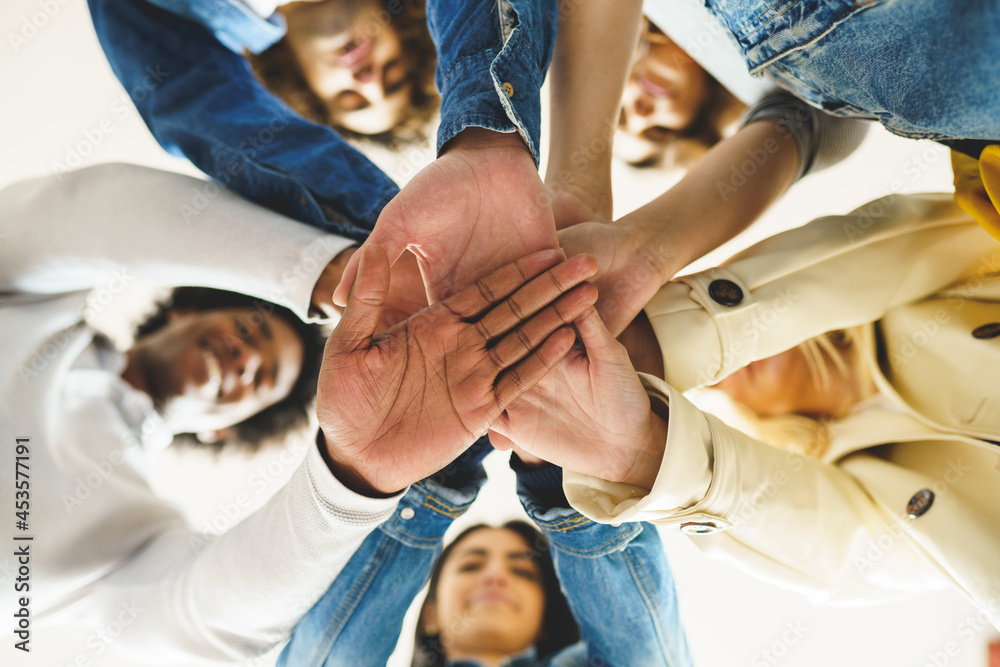 Hands of a multi-ethnic group of friends joined together as a sign of ...