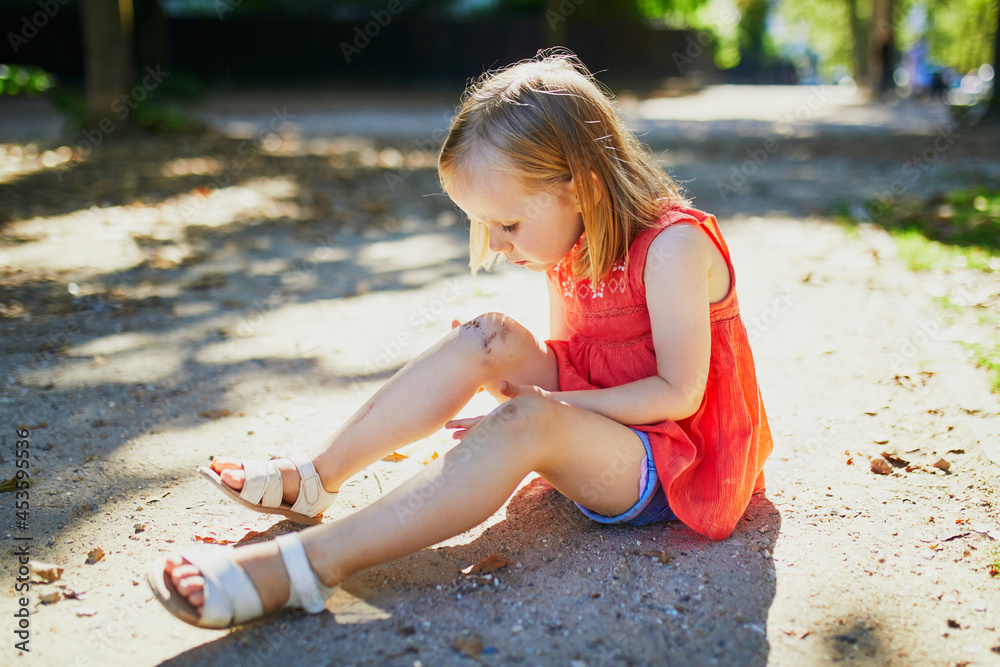 Cute little girl sitting on the ground after falling down Stock Photo ...