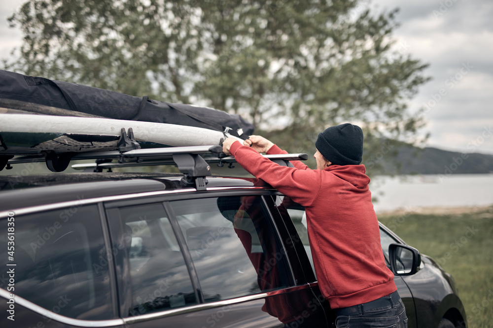 Windsurfer and camper packing and unpacking from a car's roof rack in ...