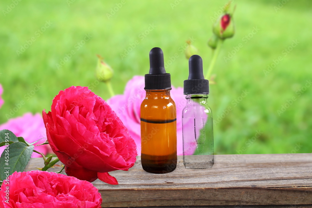 rose essential oil and rose water in glass bottle with rose flower in ...