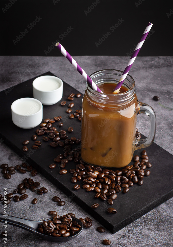 Vaso de café con leche con dos popotes y crema sobre un fondo oscuro ...
