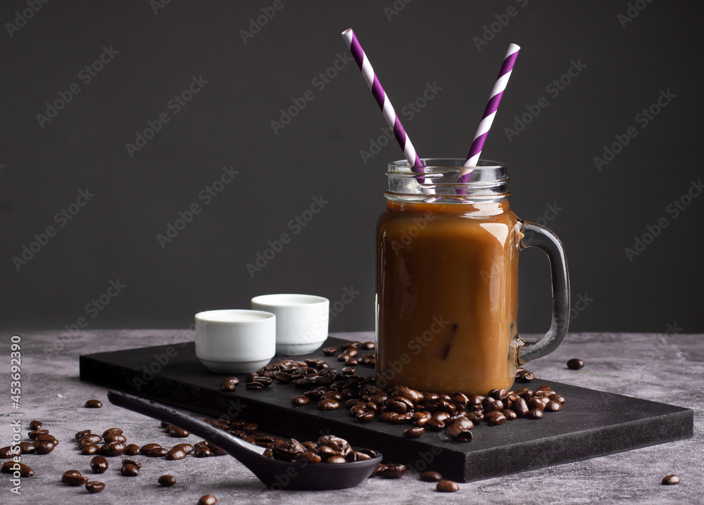 Vaso de café con leche con dos popotes y crema sobre un fondo oscuro ...