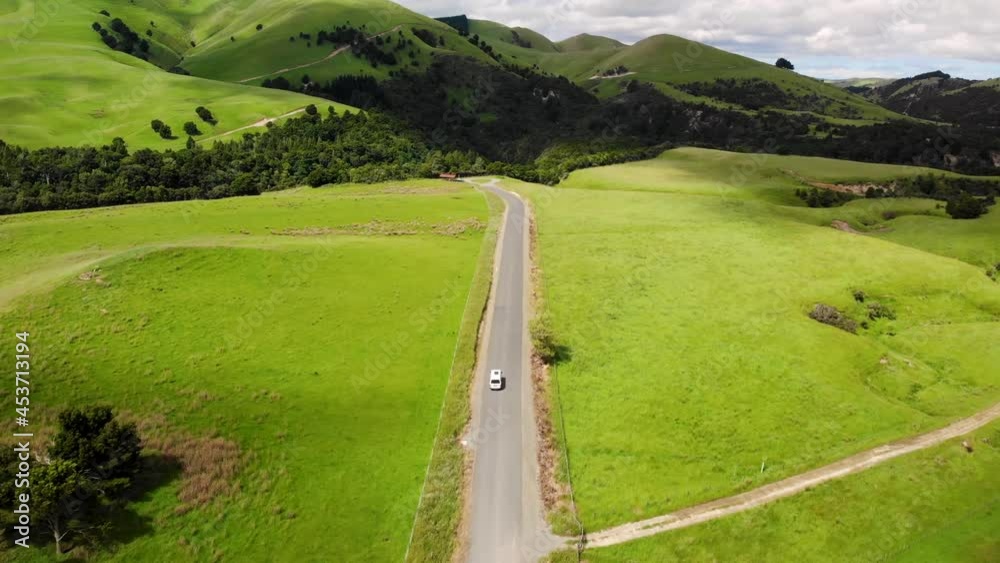 White van aerial tracking. New Zealand rural area, green hills and ...