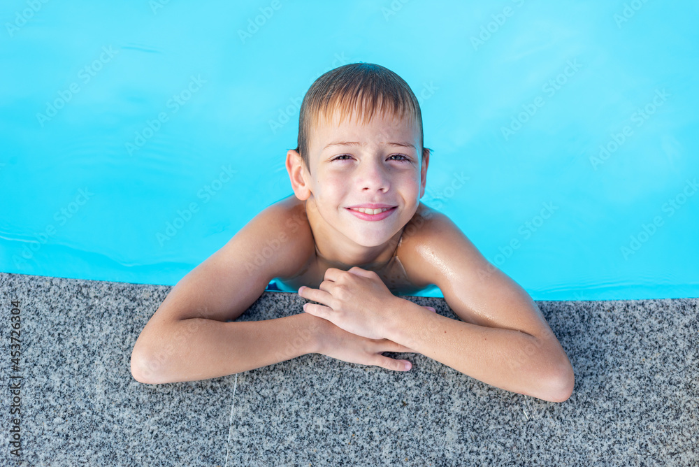 The boy on the side of the pool is smiling. The open air swimming pool ...