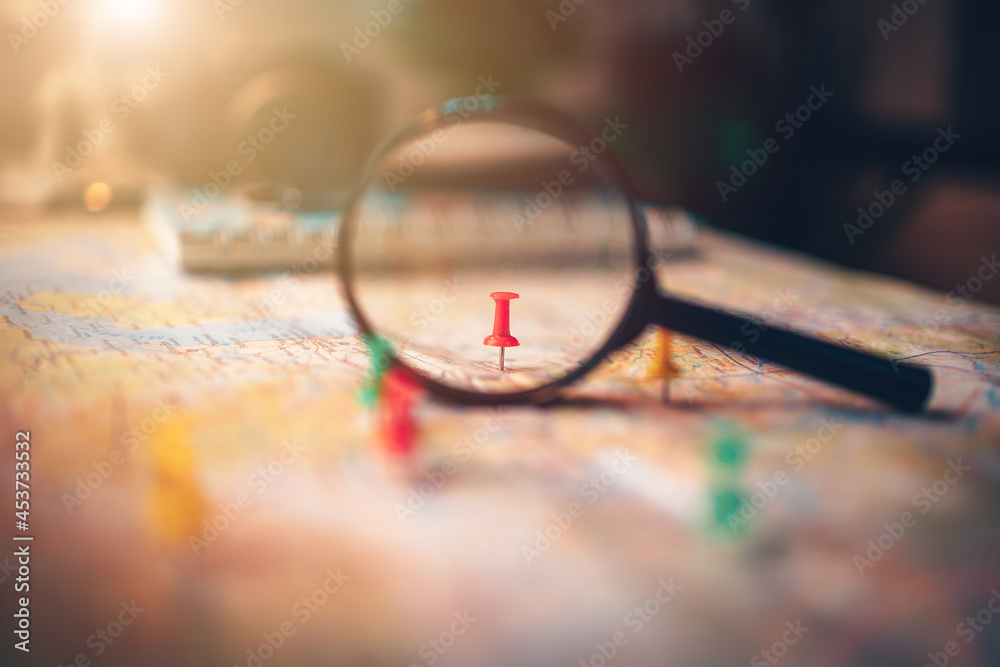 A magnifying glass with pins pinned on the map. pushpin showing the ...