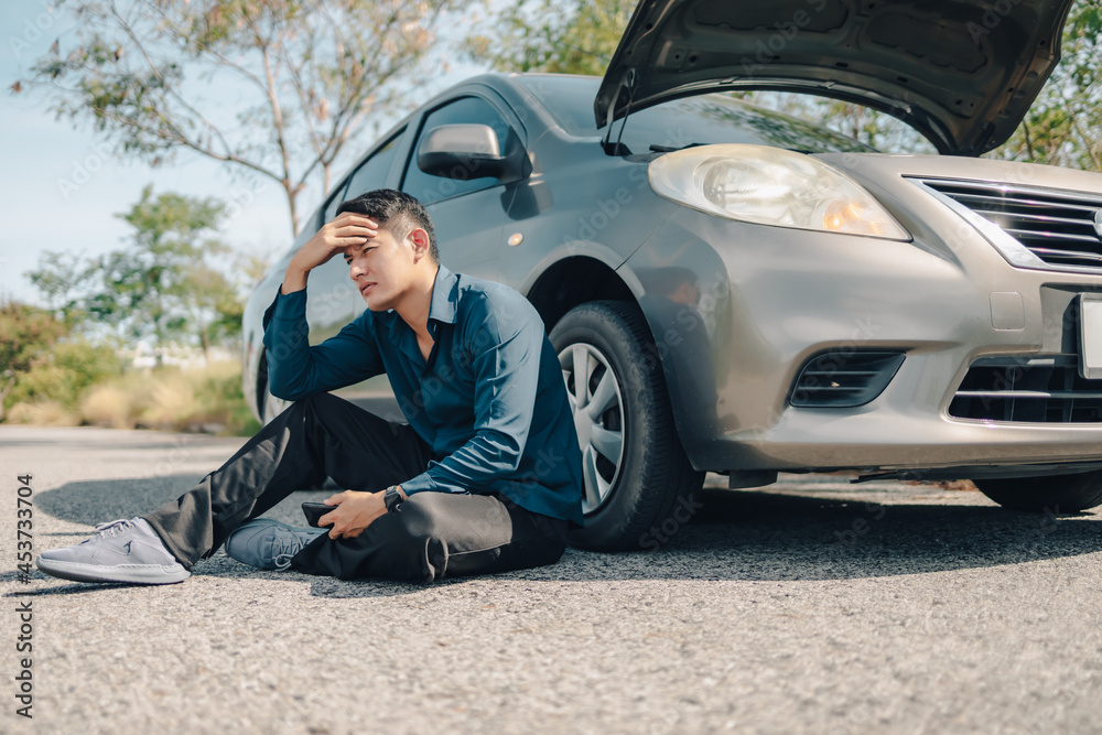 Serious man headache sitting beside car breakdown on roadside. Car ...