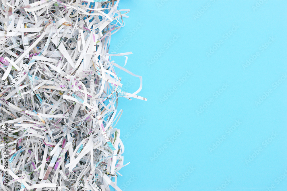 The shredded paper on light blue background. Stock Photo | Adobe Stock
