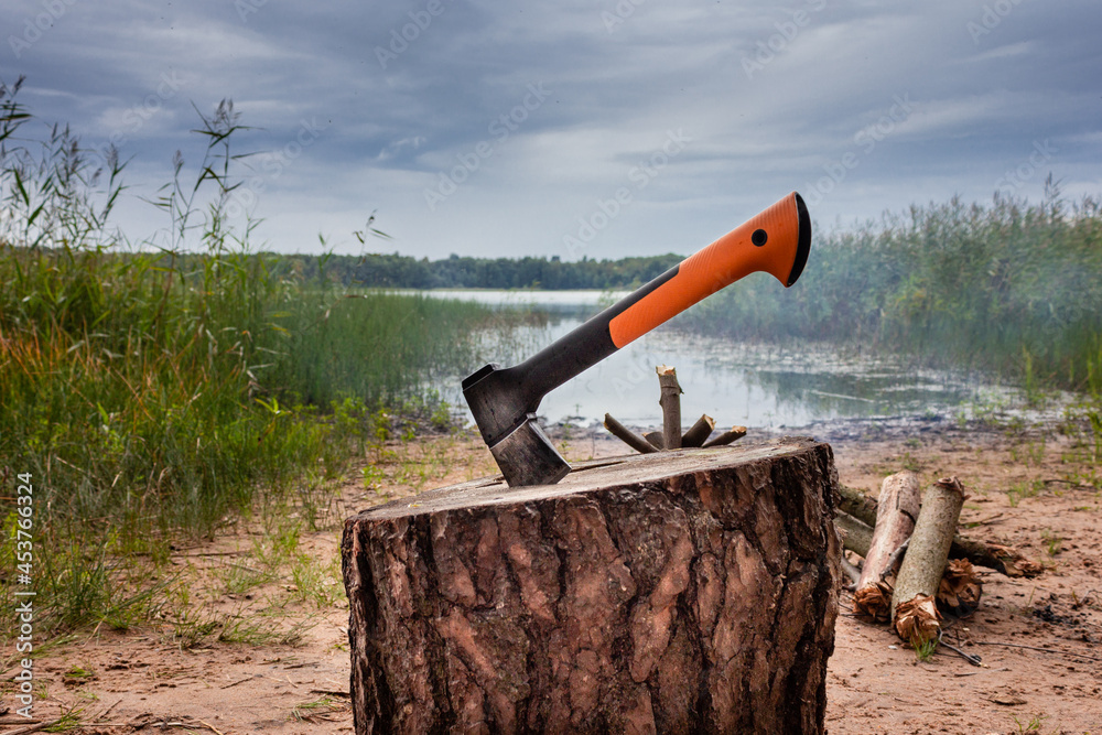 The axe is stuck in a log. Chopping wood for a fire on the background ...