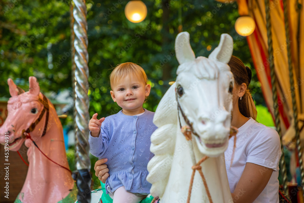 Cute baby girl with mother on the horse of old retro carousel, Prague, Czech republic Stock ...