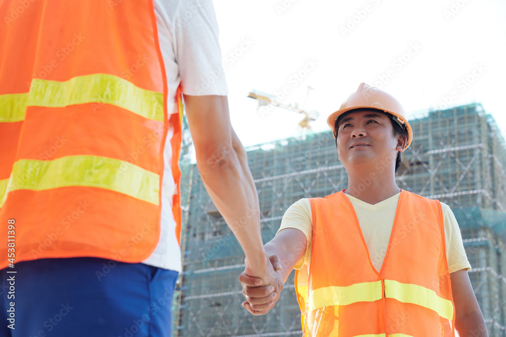 Foto de Smiling constriction worker shaking hand of contractor when ...