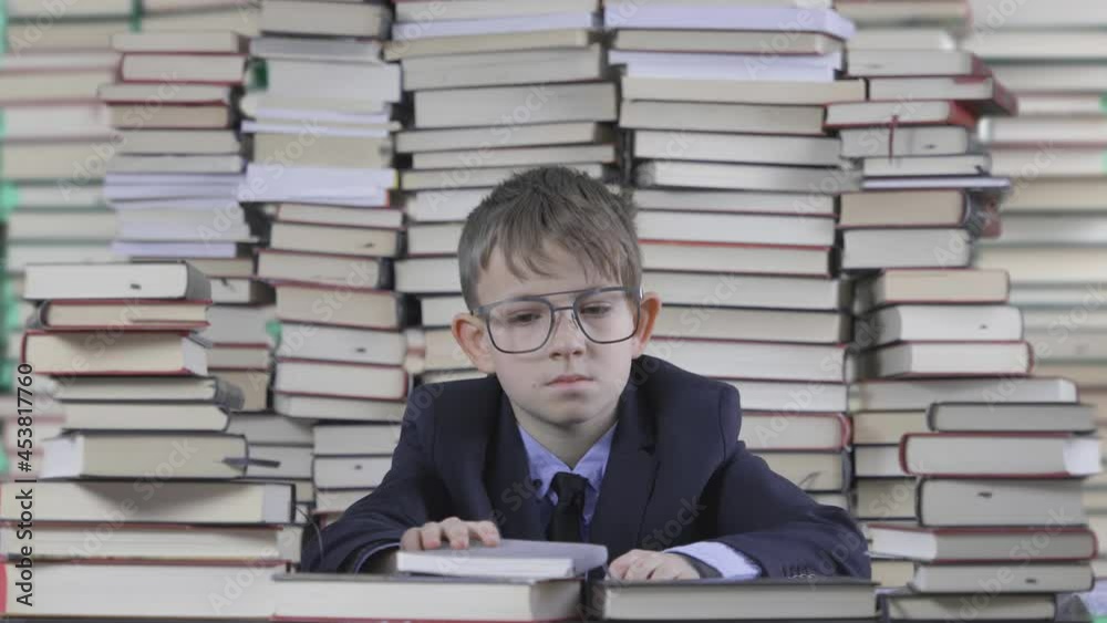 Vídeo do Stock: Tired child with suit and tie sit at desk in library ...