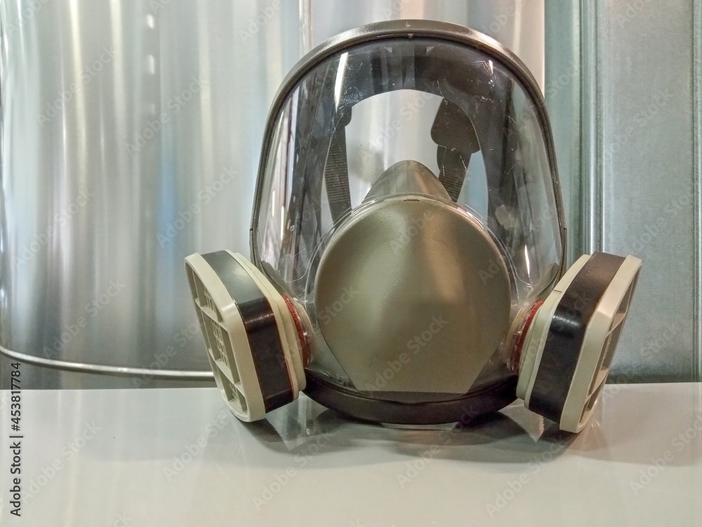 Protective half mask with a glass screen and two filters on a shiny ...