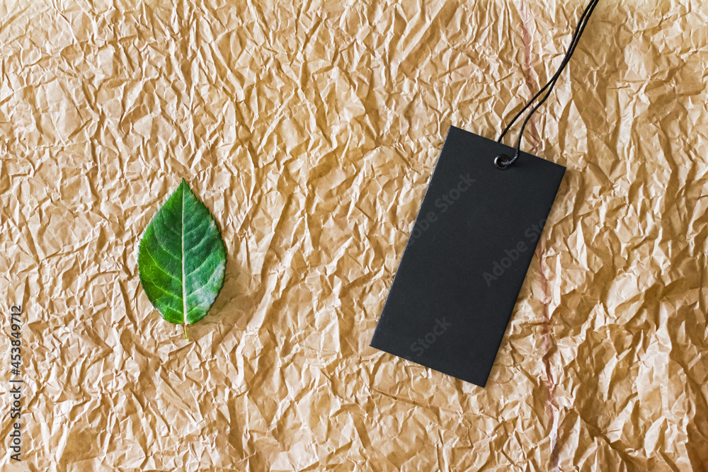 Grean leaf and black price tag on recycled material as flatlay ...