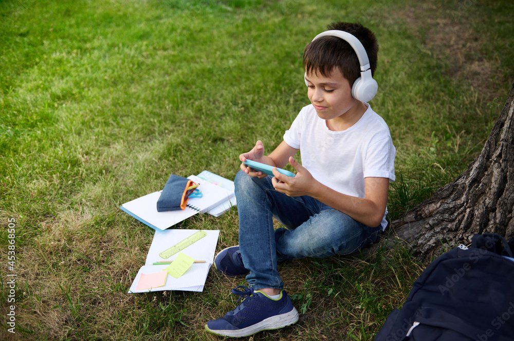 Top view. Adorable handsome elementary aged schoolboy wearing wireless ...
