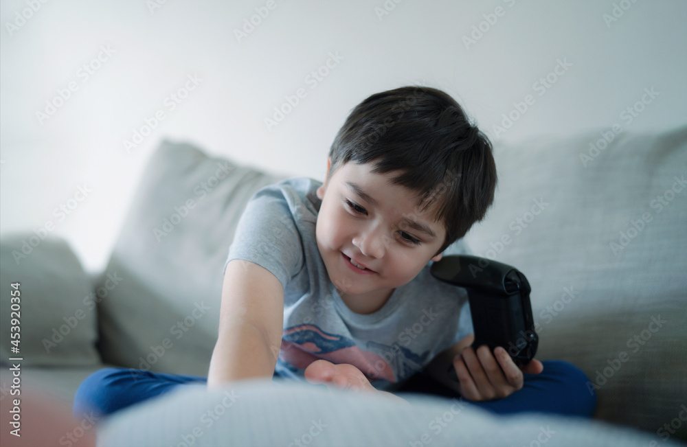 Young boy playing video games online, Candid shot Happy mixed race ...
