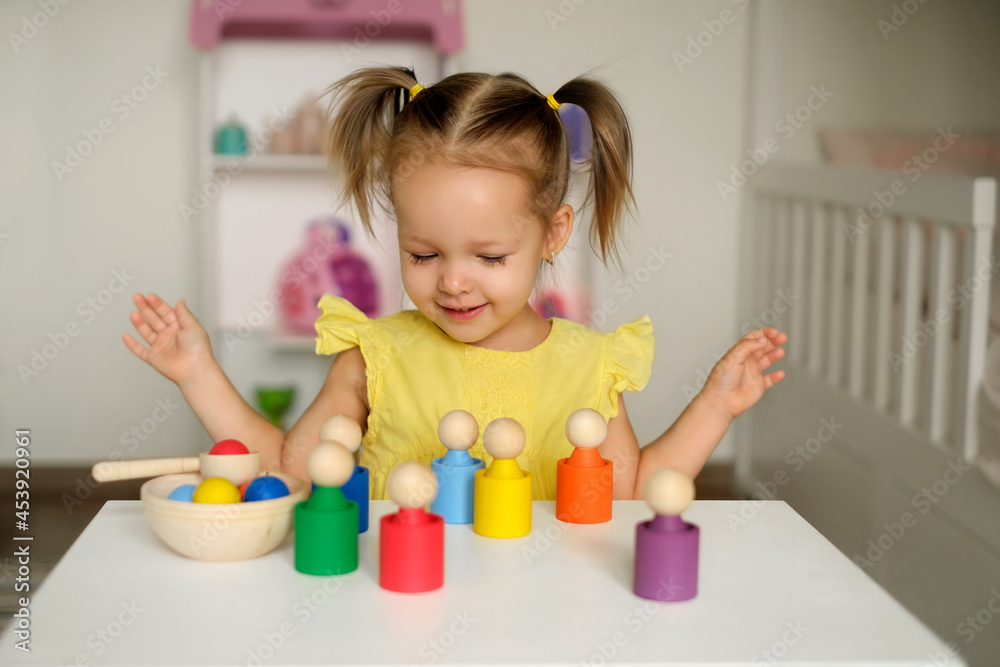 The girl learns colors by playing with wooden cylindrical toy colored ...