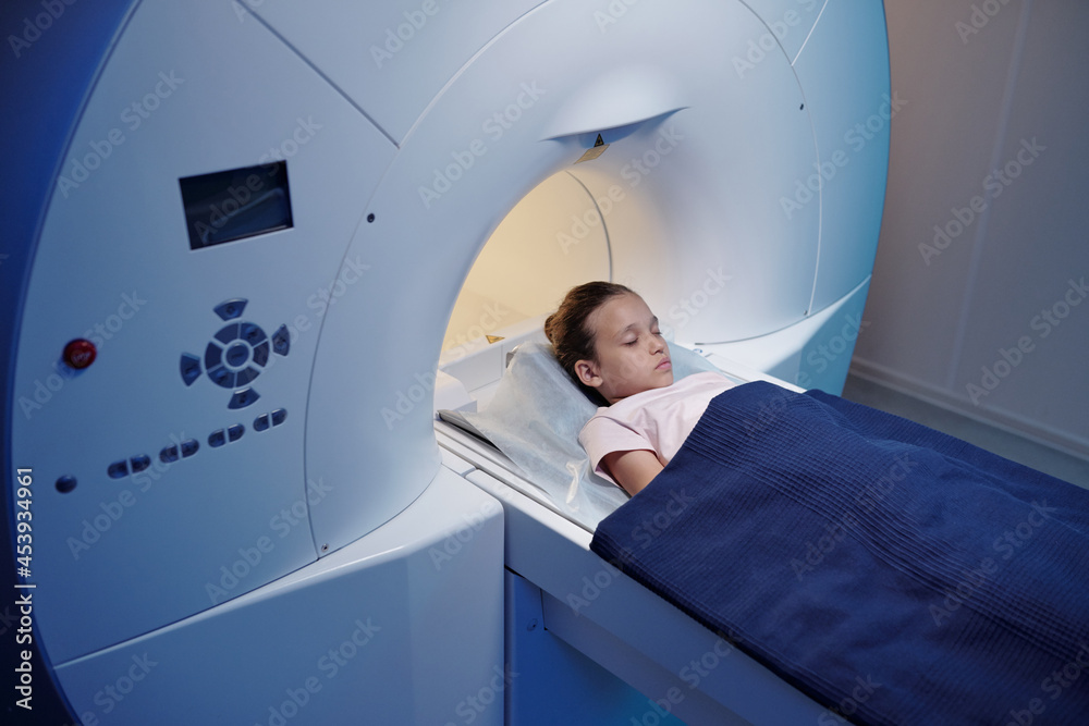 Little girl with her eyes closed moving into mri scan machine before ...