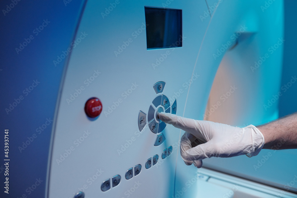 Gloved hand of radiographer pressing start button on panel of mri scan ...