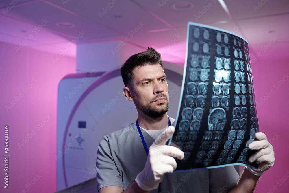 Foto de Contemporary radiologist in gloved and uniform looking at x-ray ...