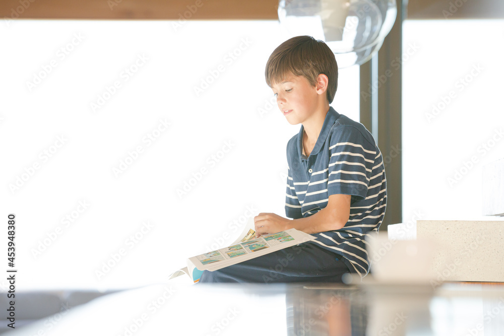 Boy reading magazine in modern house Stock Photo | Adobe Stock