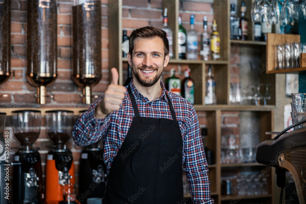 Waitress shows a thumbs up. Attractive male is standing in a cafe and ...