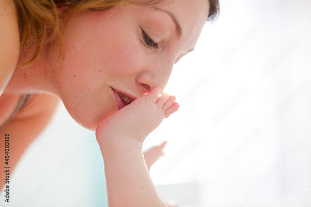Mother kissing baby girl's feet Stock Photo | Adobe Stock