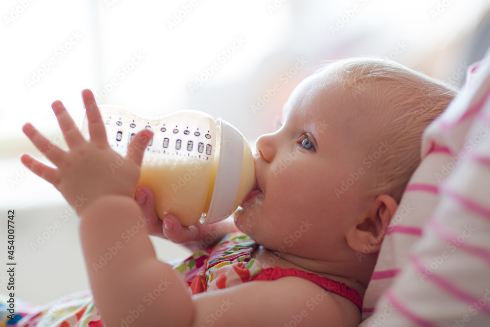 Baby girl drinking from bottle Stock Photo | Adobe Stock