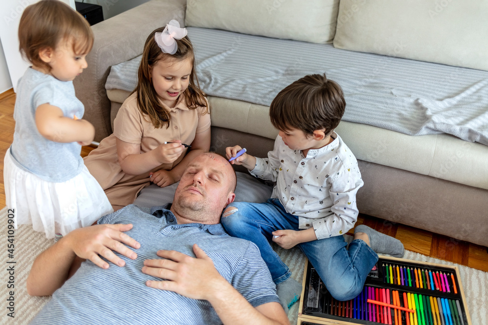 Children carefully paints their father's face during family games ...