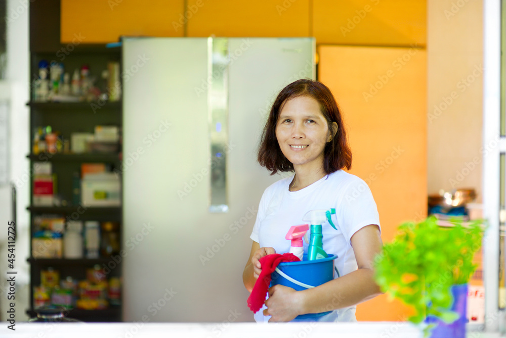 Asian woman carrying a bucket of detergents in the kitchen.Beautiful ...