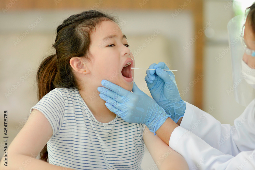 Female pediatrician using a swab to take a sample from a patient's ...