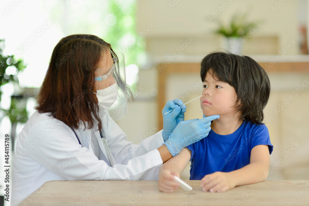 Female pediatrician using a swab to take a sample from a patient's nose ...