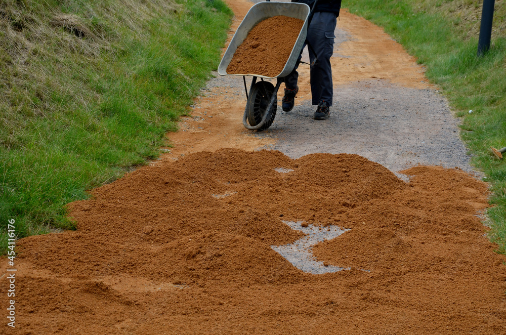 Sand wheeling. garden wheelbarrow carries a worker and pours on piles ...
