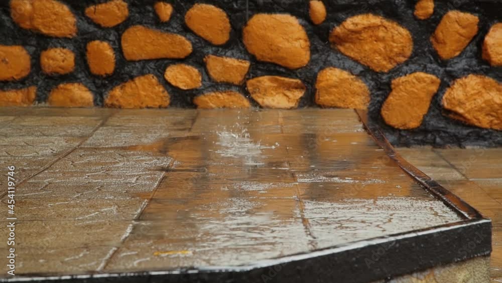 Raindrops dripping onto concrete paving slabs. Puddle forms on step of ...