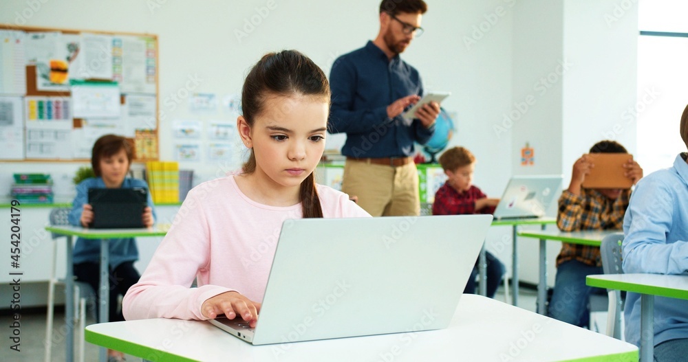 Close up of concentrated Caucasian little girl sitting at desk at ...