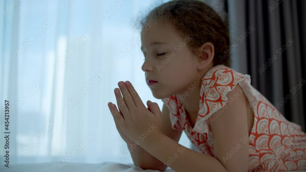 Little girl is praying in her room.Close up portrait of child concept ...