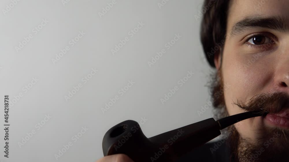 Young happy man is smoking retro style pipe and smiling standing on ...