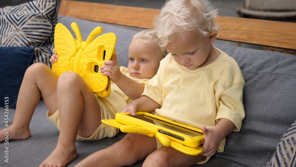 Tablet time for twin toddlers, each with its own yellow cased tablet ...
