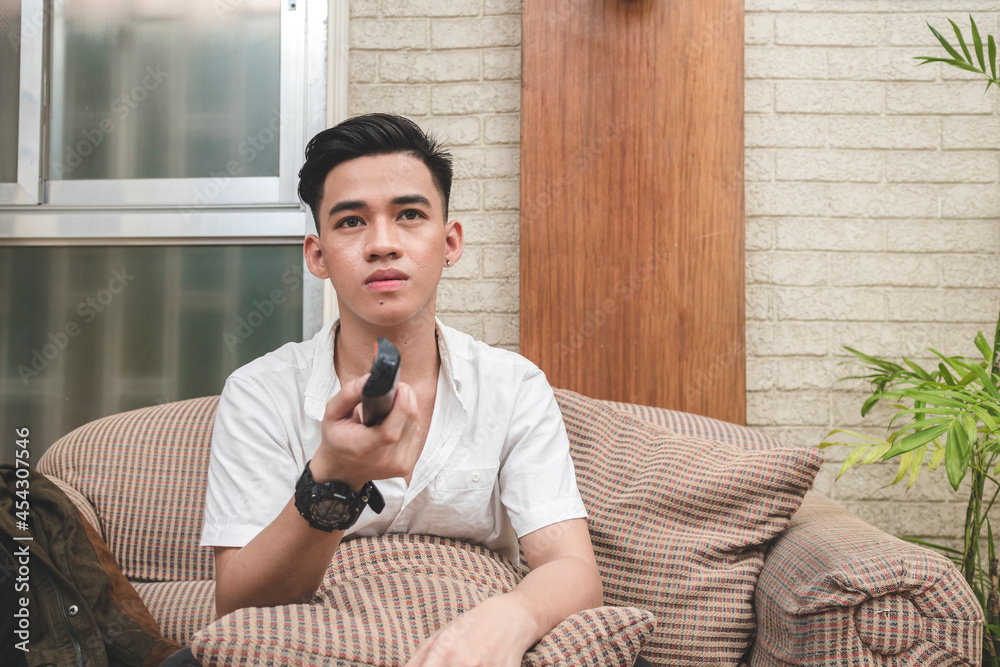 A young Gen Z man selects a movie from a streaming service with a ...