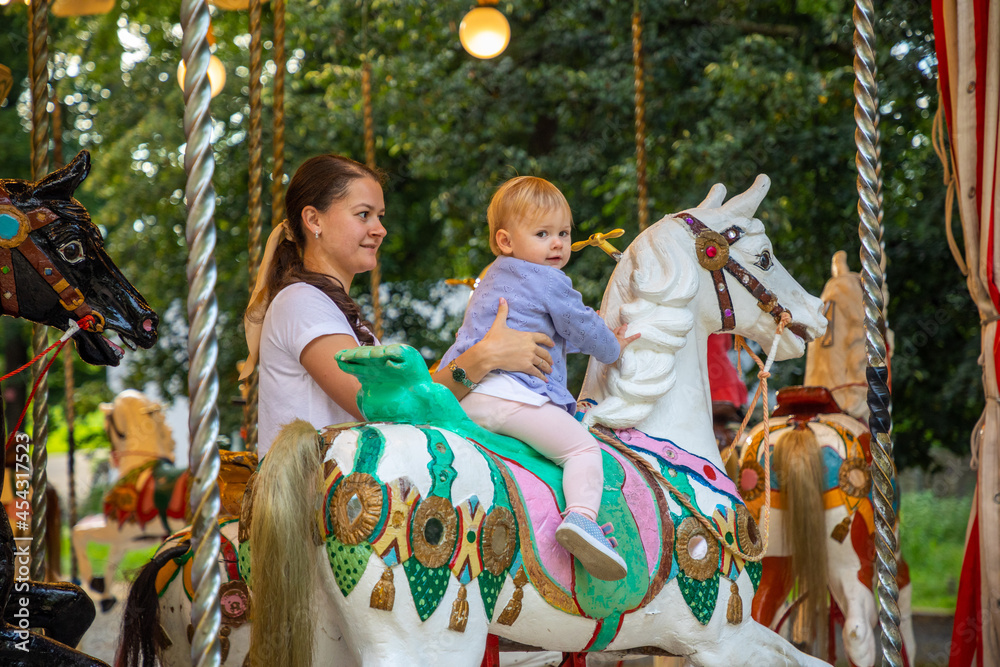 Cute baby girl with mother on the horse of old retro carousel, Prague, Czech republic Stock ...